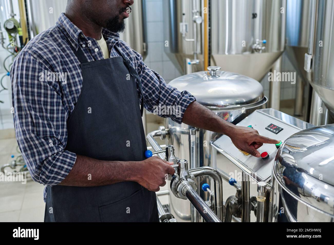 Close-up of African American worker in apron pushing the button to turn ...