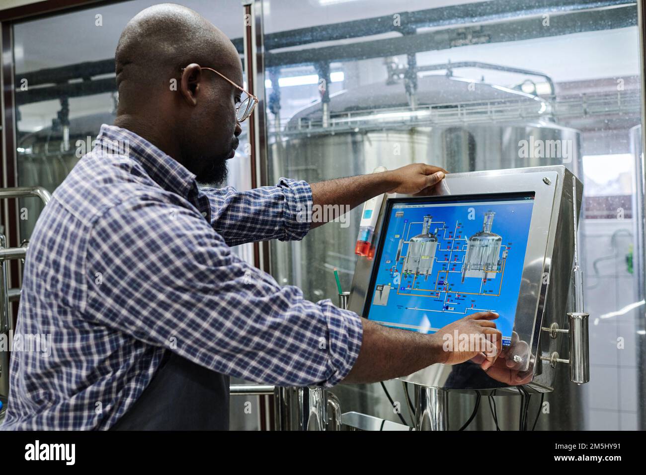 African American engineer working on computer, he looking at monitor to ...