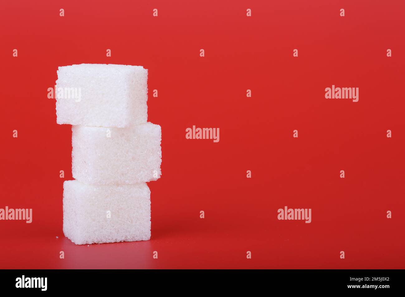 stack of white sugar cubes isolated on red background Stock Photo - Alamy
