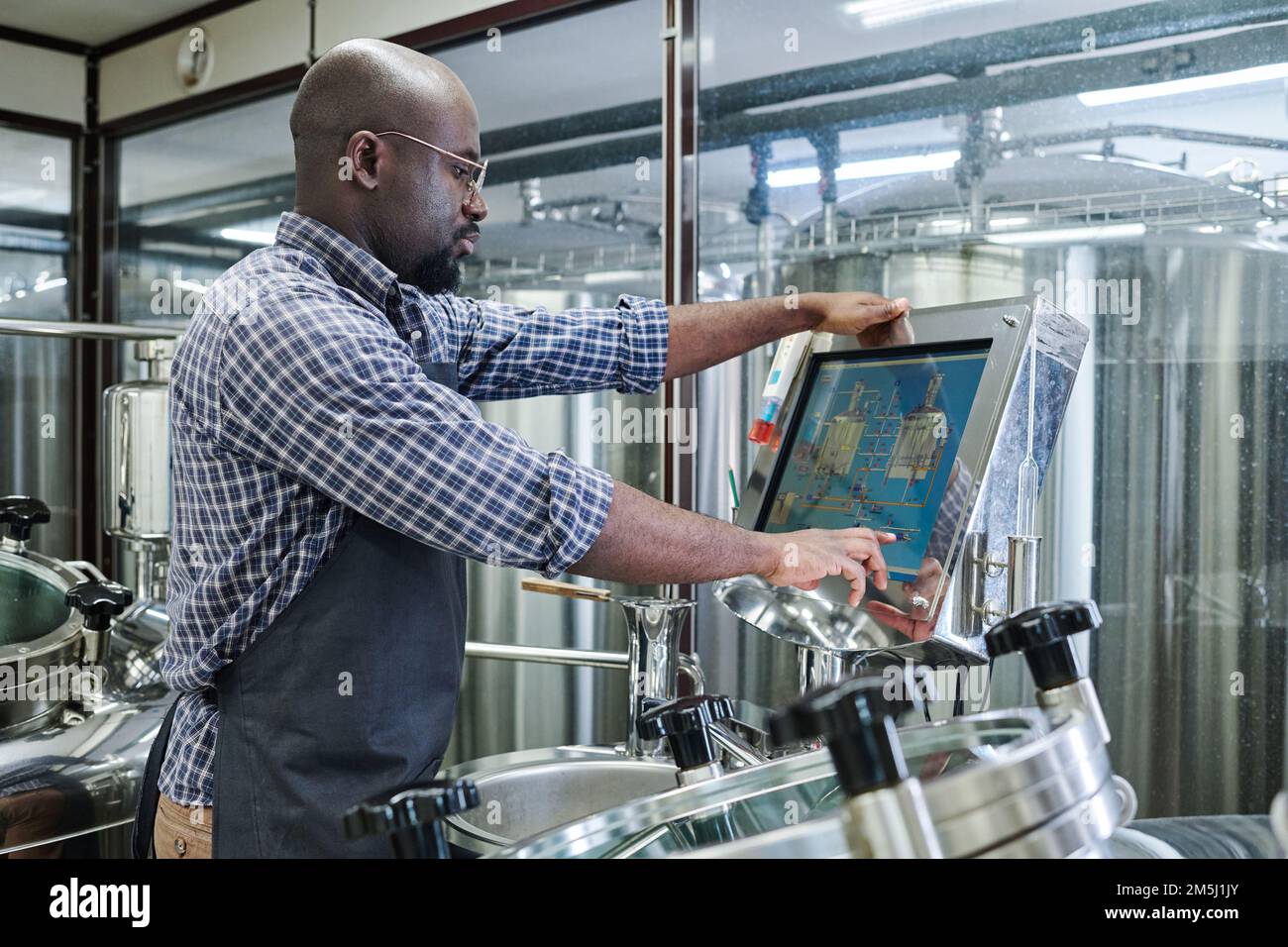 African American engineer controlling equipment with computer monitor ...