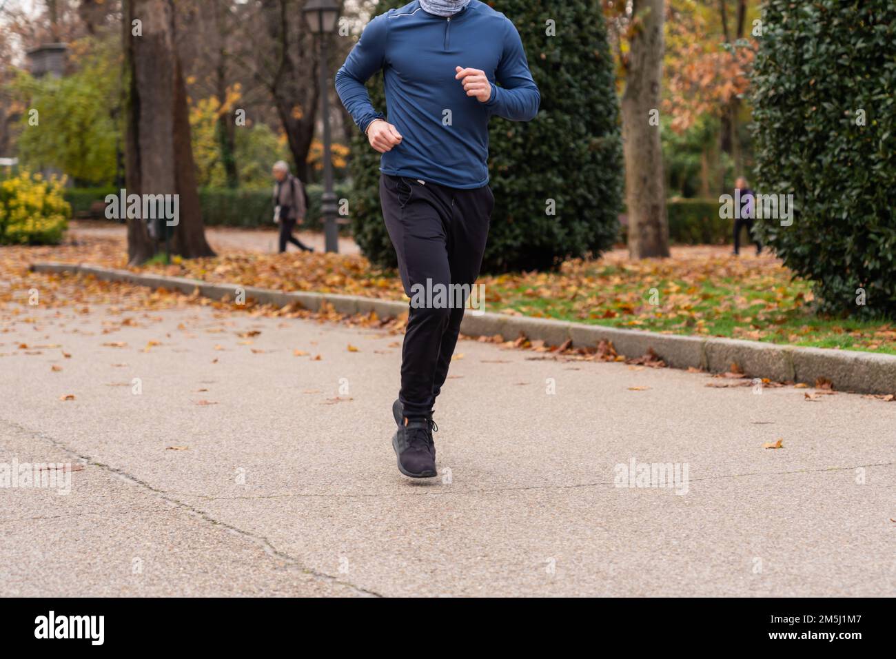 Unrecognizable sportsman running on asphalt path covered with dry ...