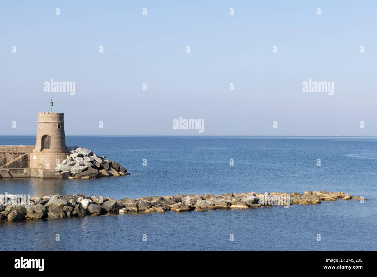 Old small lighthouse and stone wave breakers of Recco on a sunny summer ...
