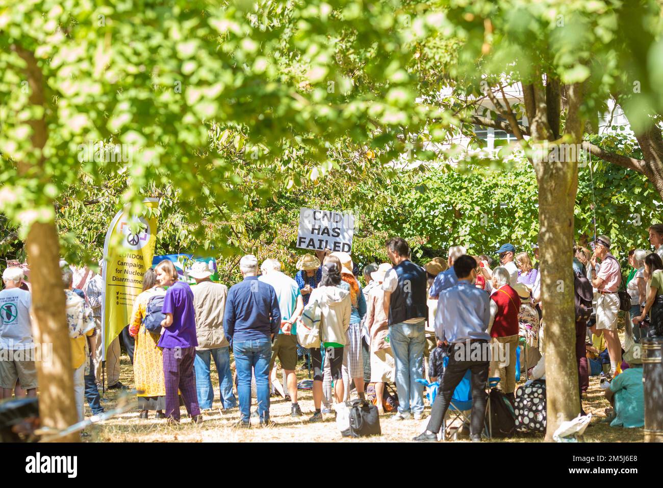 People gather near the cherry tree planted in memory of the victims of ...
