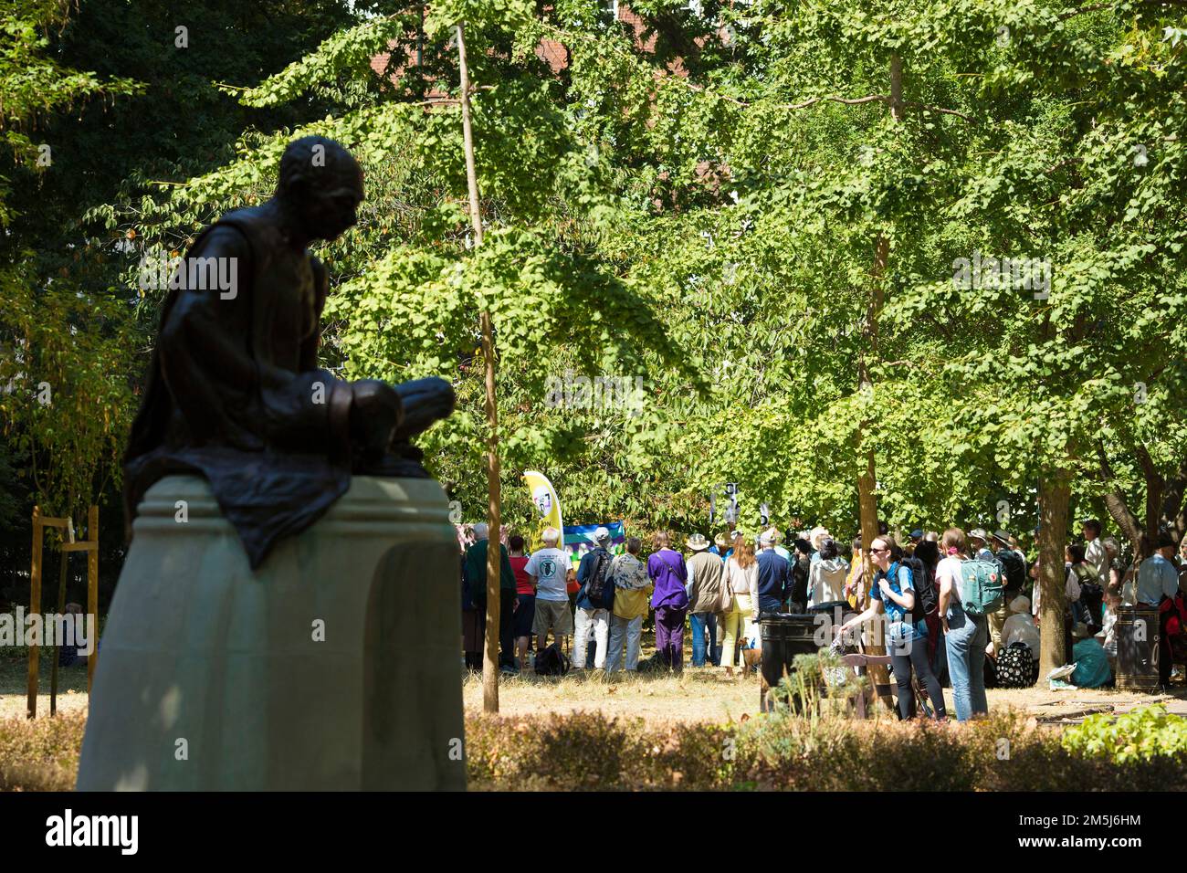 Behind a statue of Mahatma Gandhi, people gather near the cherry tree ...