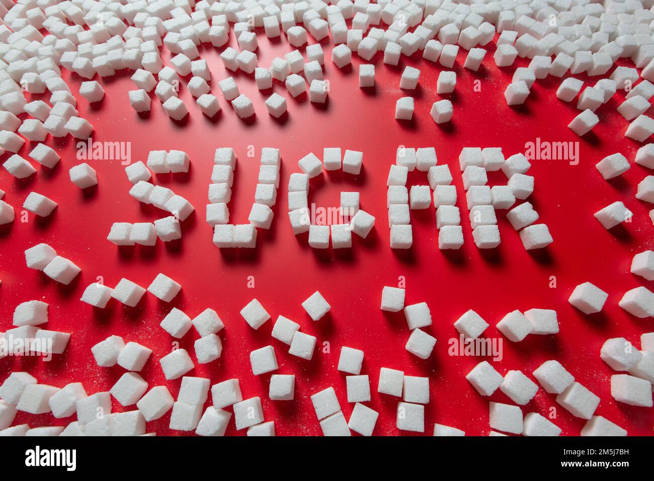the word sugar is made up of sugar cubes on a red background. photo on ...