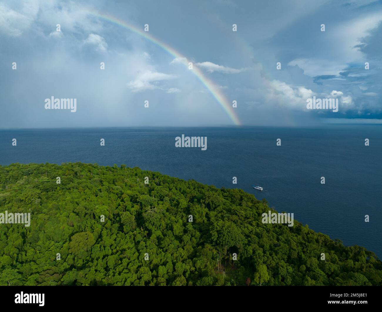 A bright rainbow appears behind a remote tropical island in the Solomon ...