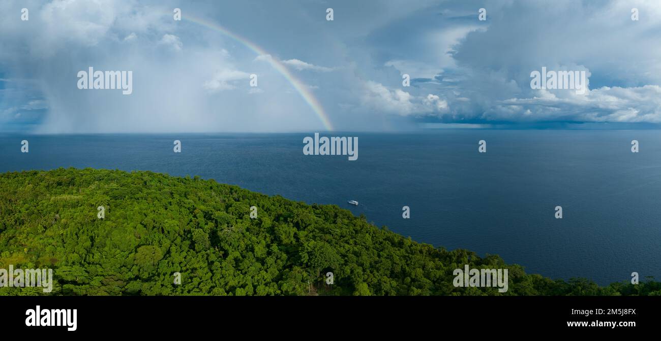 A bright rainbow appears behind a remote tropical island in the Solomon ...