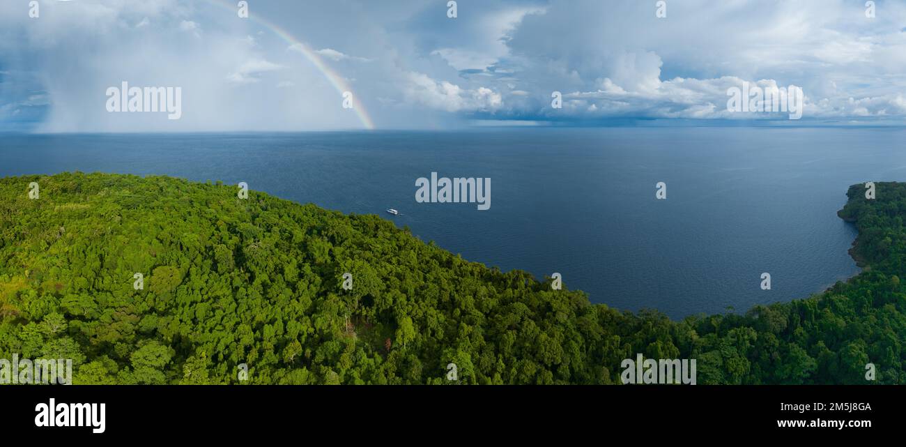 A bright rainbow appears behind a remote tropical island in the Solomon ...