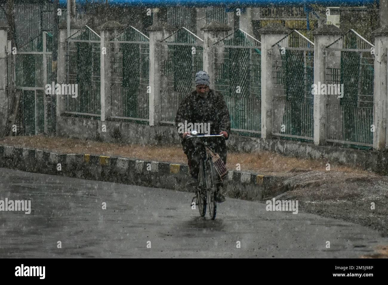 A cyclist rides along the road during the season's first snowfall in ...