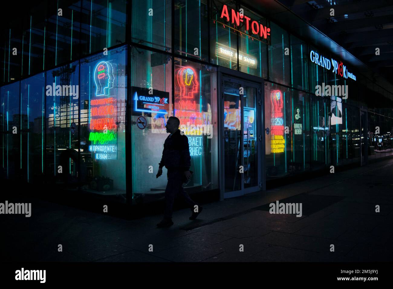 A man passes by restaurant's windows illuminated at night. Moscow ...