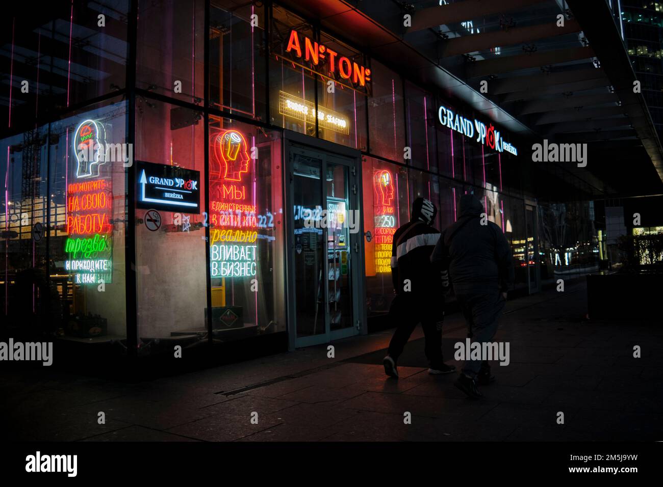 People passing by restaurant's windows illuminated at night. Moscow ...