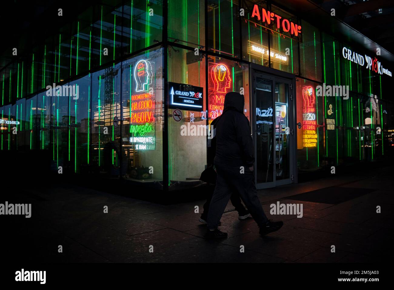 People passing by restaurant's windows illuminated at night. Moscow ...