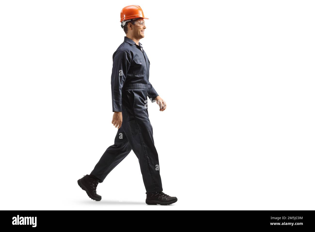 Full length profile shot of a factory worker wearing a helmet and ...
