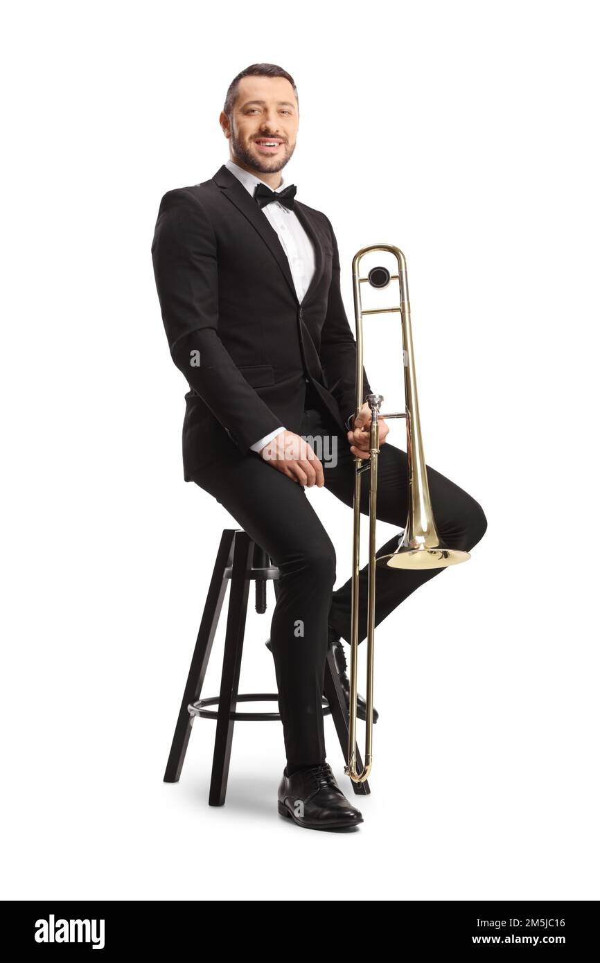 Male musician in a black suit and bow-tie sitting on a chair with a ...