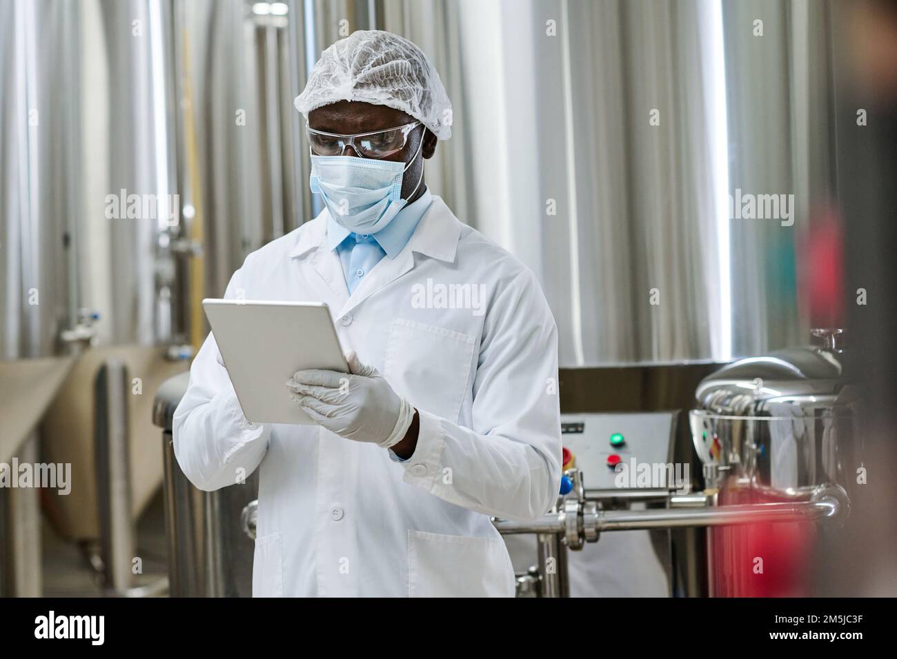 African American specialist in white coat and mask using tablet pc ...