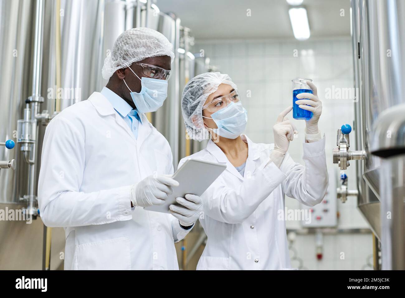 Multiethnic couple of scientists conducting research in team at factory ...