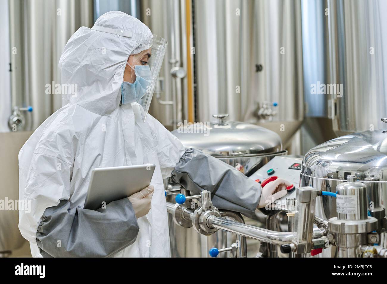 Engineer in protective workwear controlling machinery with panel at ...