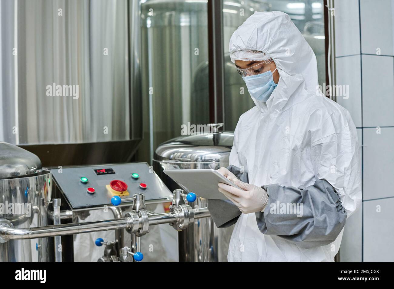 Engineer in protective costume working on digital tablet standing ...