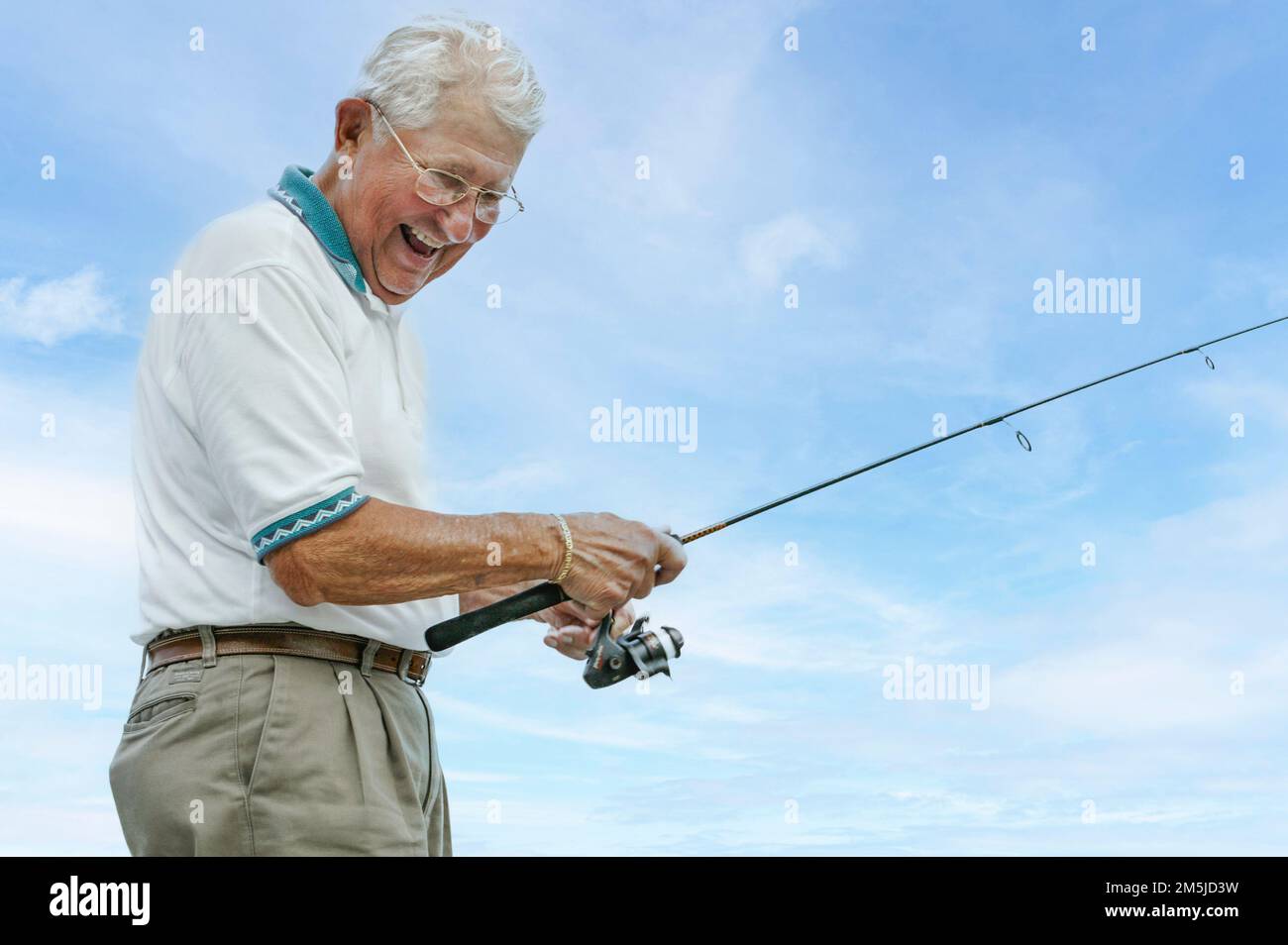 A senior enjoys the thrill of fishing from a dock on a nice summer day ...