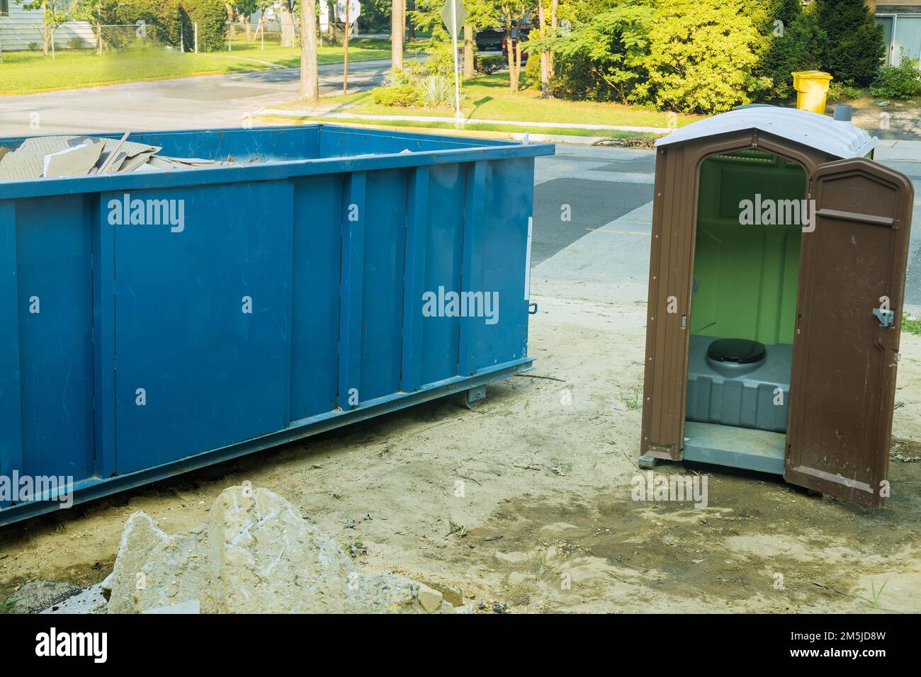 Construction garbage dumpster and portable restroom in new house under ...
