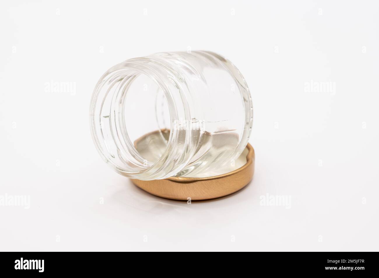close-up of a small empty clear jam preserve glass jar with a a bronze ...