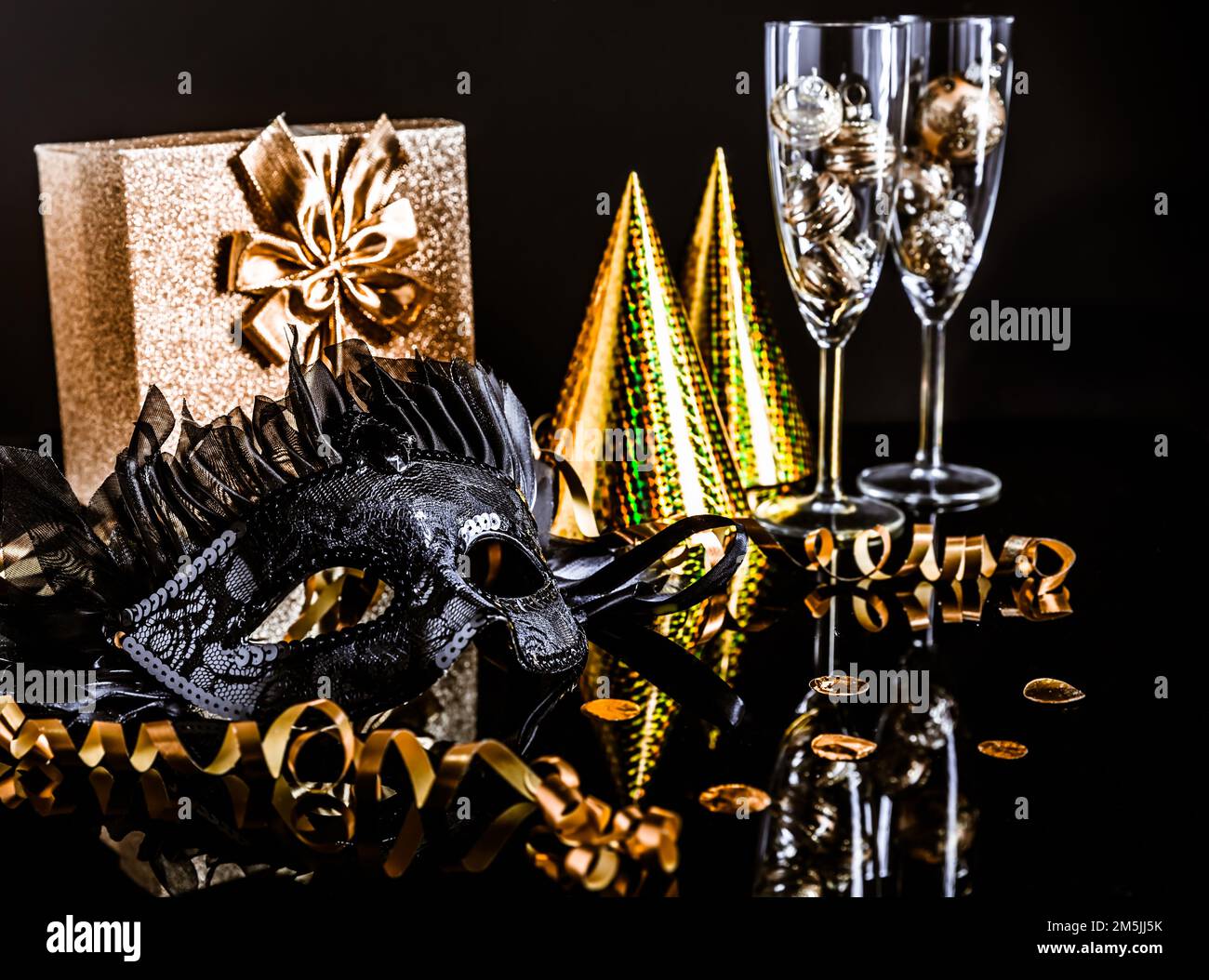 Carnival mask with present and party hut and ribbon on black background ...