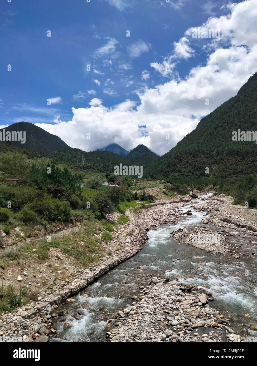 A landscape scene of green plains by lake with green mountains under a ...