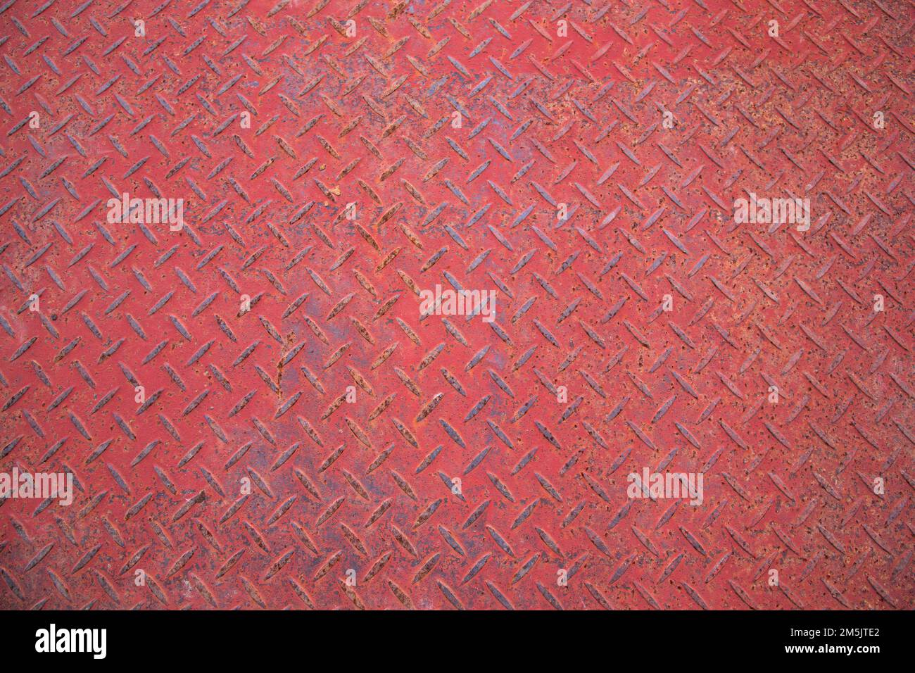 The view of a red-patterned metallic surface creates an uneven backdrop ...