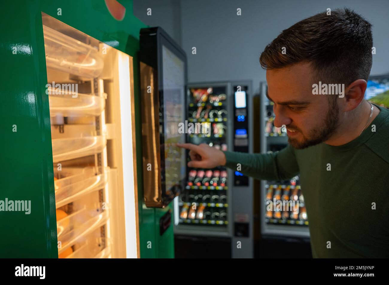 Caucasian man buys freshly squeezed orange juice from vending machine ...