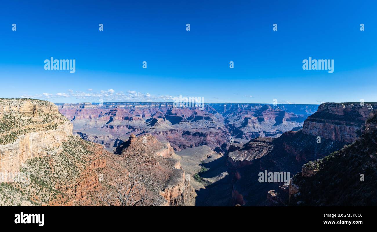 A panorama of the Grand Canyon in late morning sun with a blue, nearly ...