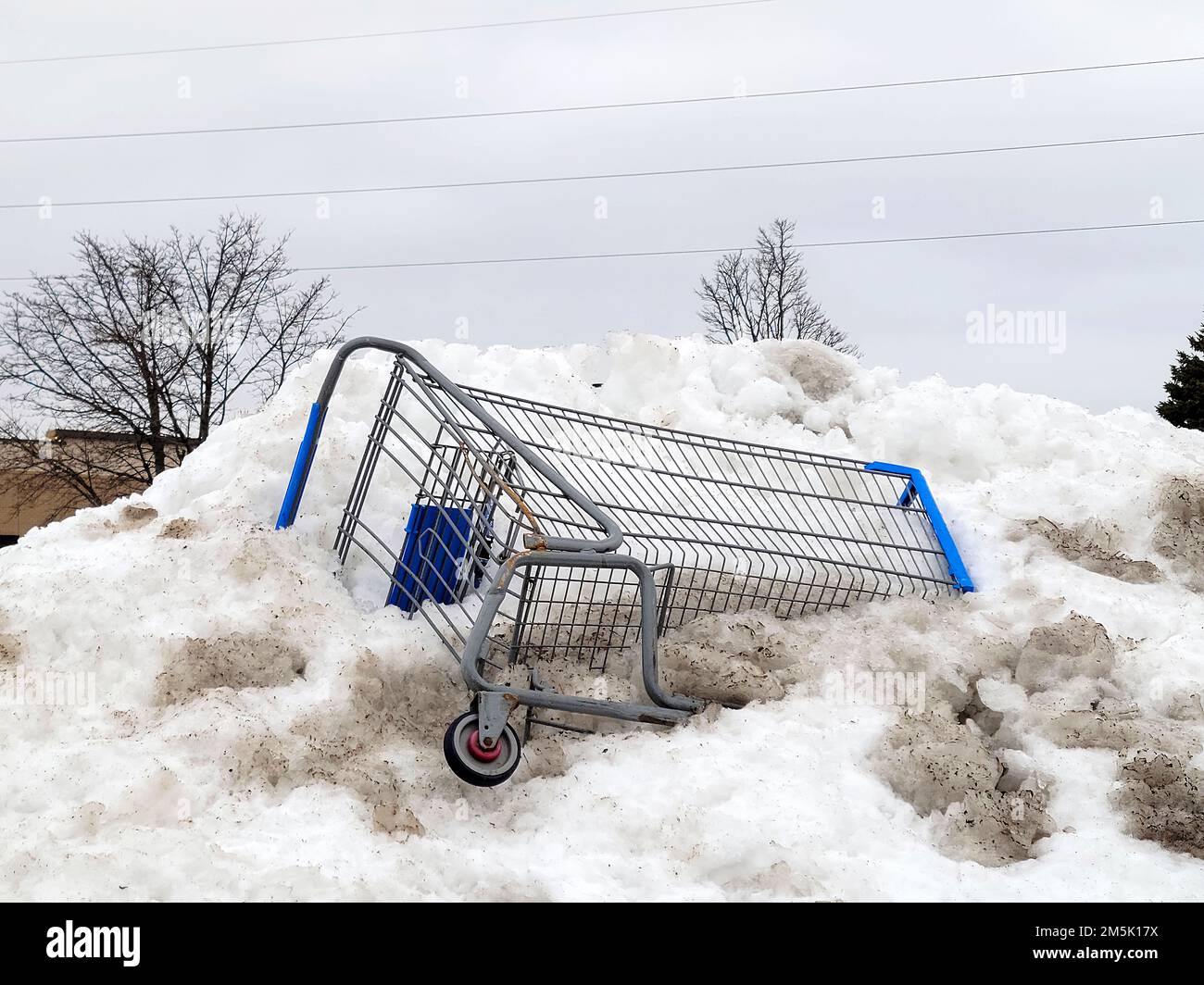 Half-buried shopping cart in a dirty snow bank Stock Photo - Alamy