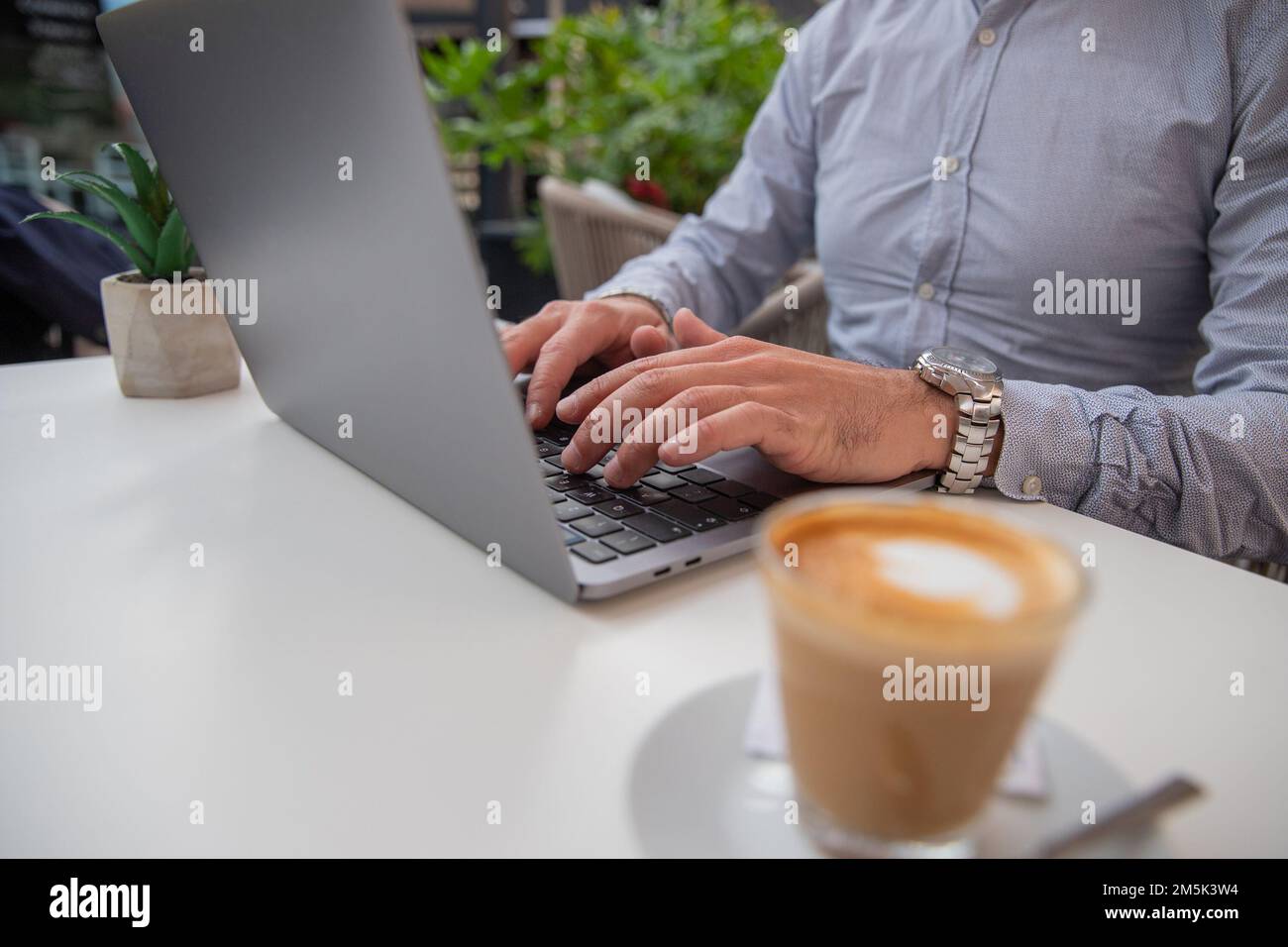 Hands of a businessman typing on laptop with coffee on the table ...