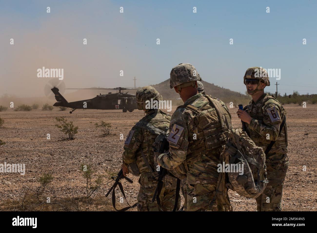 Four competitors watch as a UH-60 Black Hawk takes off during the ...