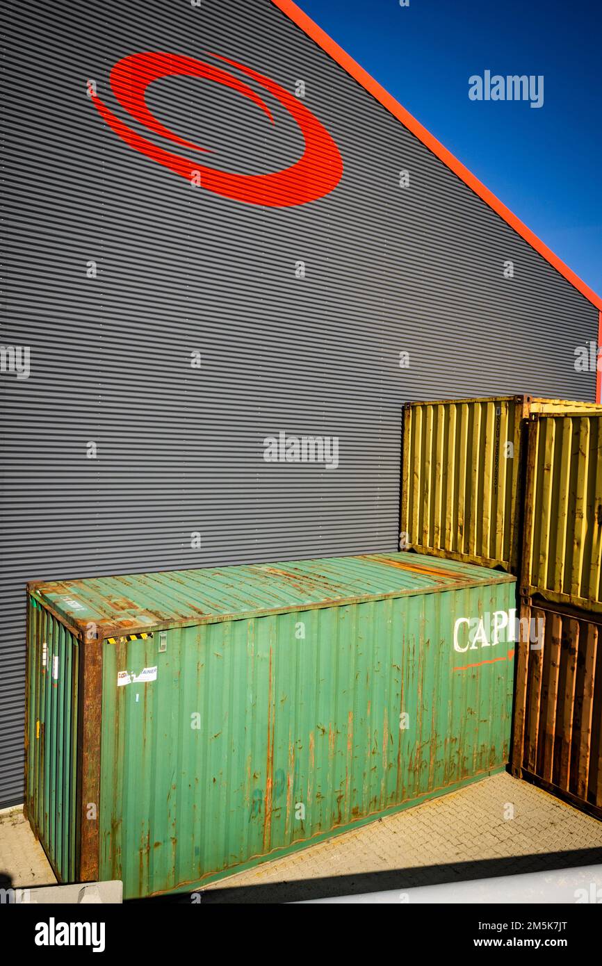 Shipping containers piled up beside a building with metal siding in ...