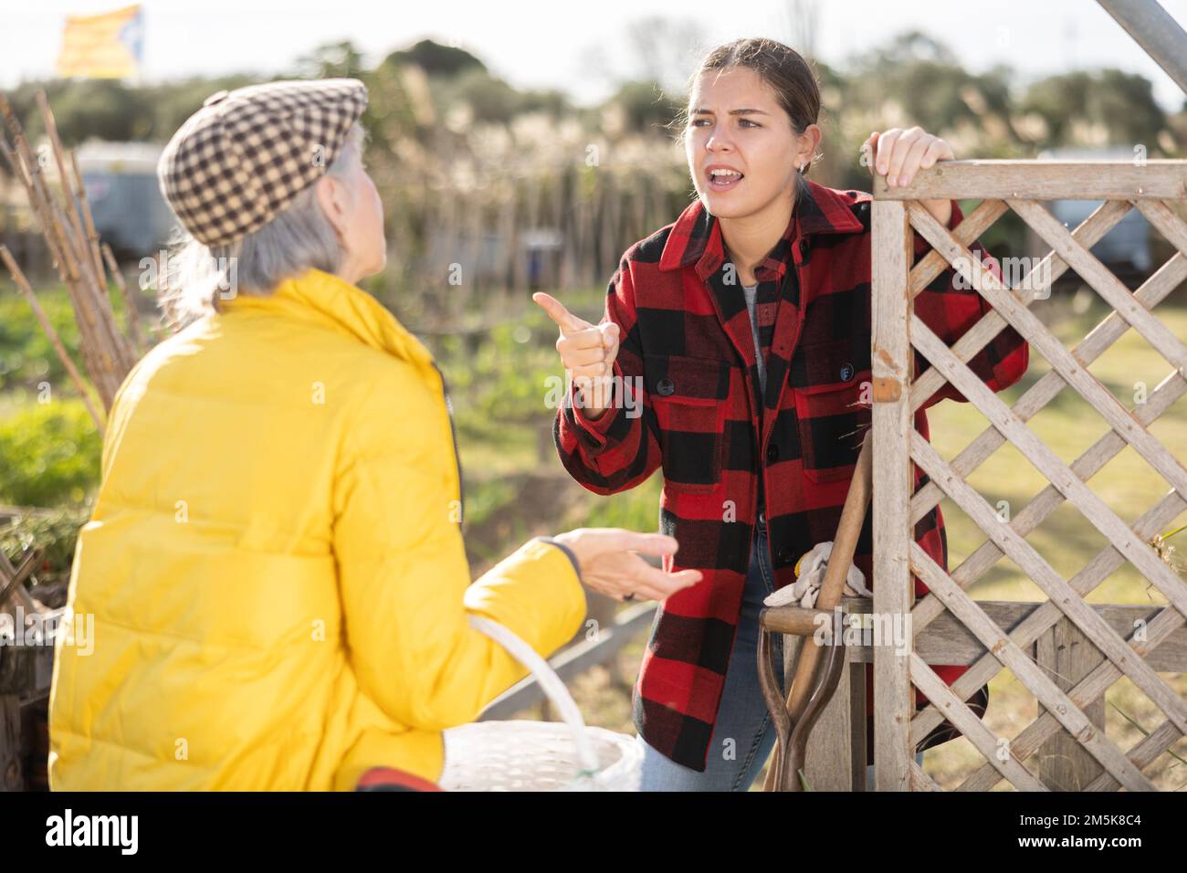 Two upset young and old female neighbors disagree with each other while ...