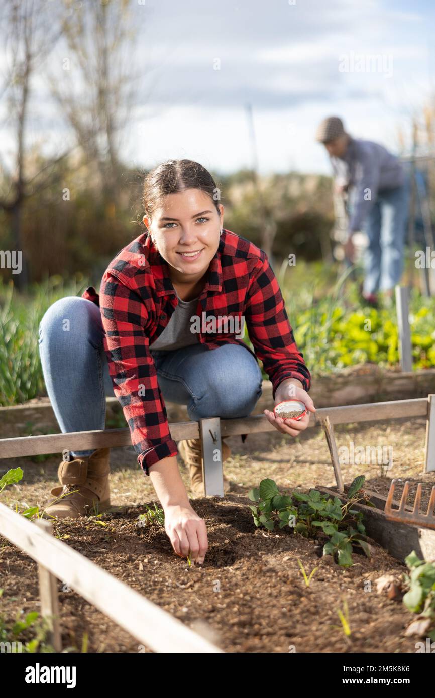 Young woman planting seeds on beds in garden Stock Photo - Alamy