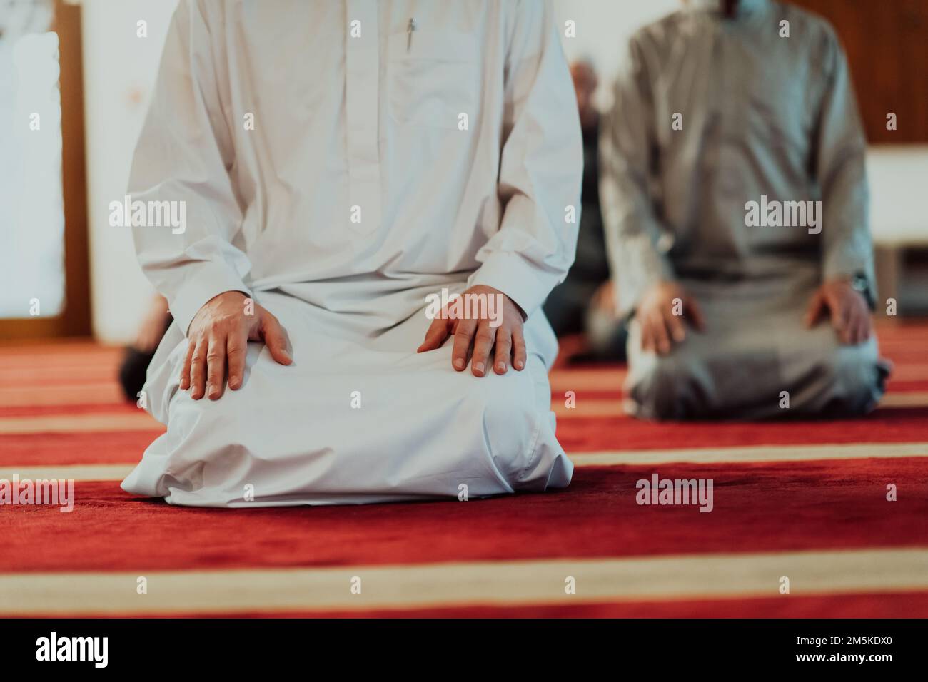 A group of Muslims in a modern mosque praying the Muslim prayer namaz ...