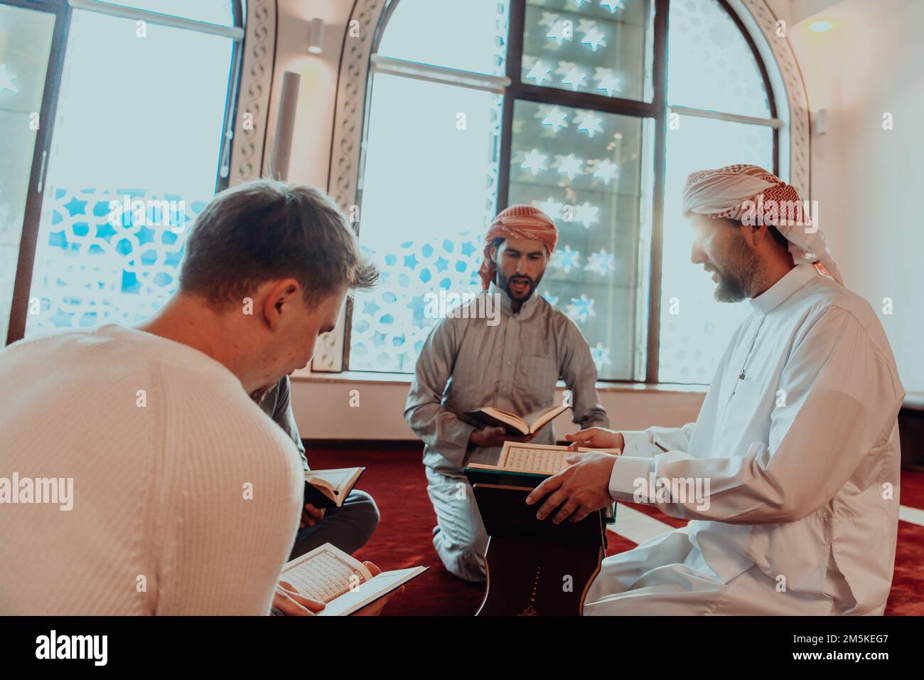 A group of Muslims reading the holy book of the Quran in a modern ...