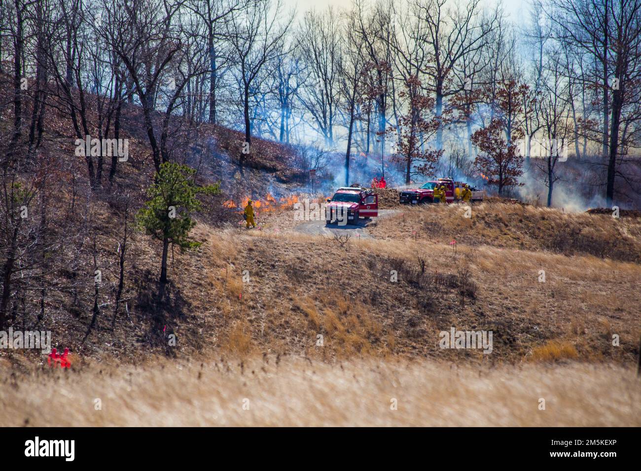 Firefighter using a blow torch to light the perimeter of the fire area ...