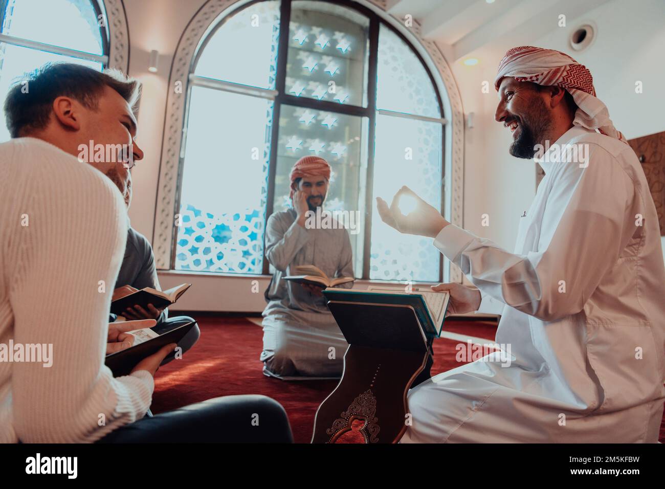 A group of Muslims reading the holy book of the Quran in a modern ...