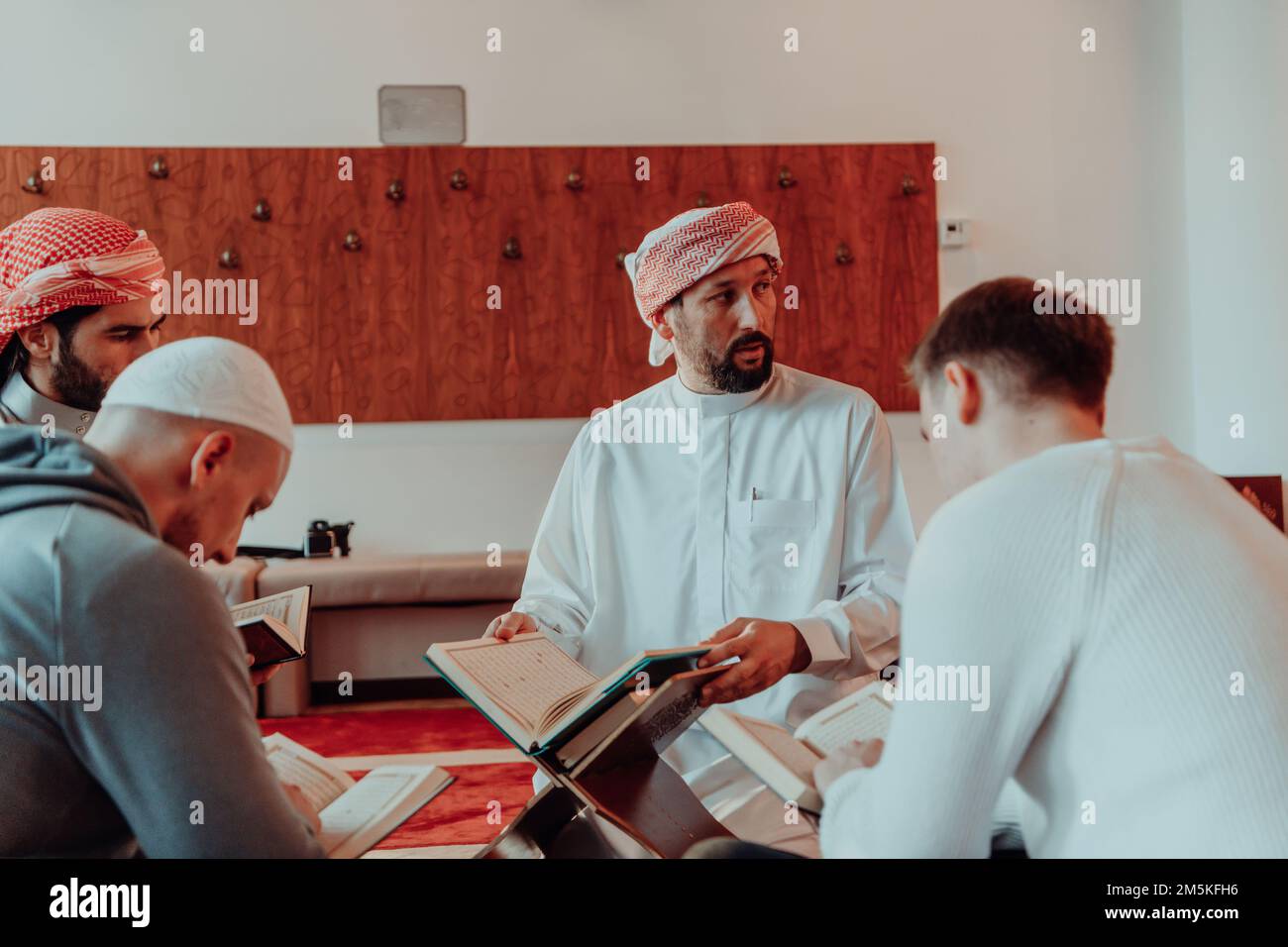 A group of Muslims reading the holy book of the Quran in a modern ...
