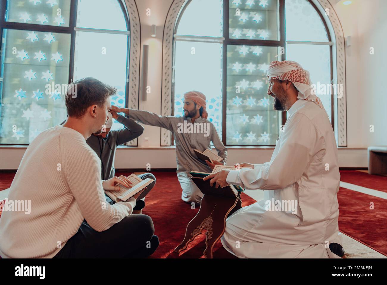 A group of Muslims reading the holy book of the Quran in a modern ...