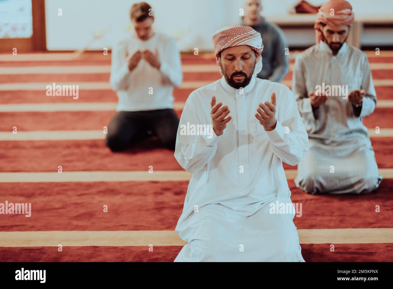 A group of Muslims in a modern mosque praying the Muslim prayer namaz ...