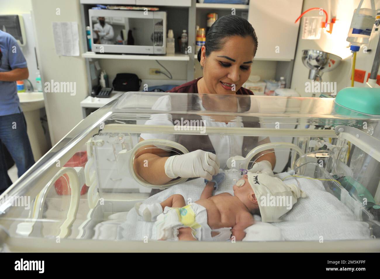 nurse with baby in nursery or intensive therapy or baby incubators ...