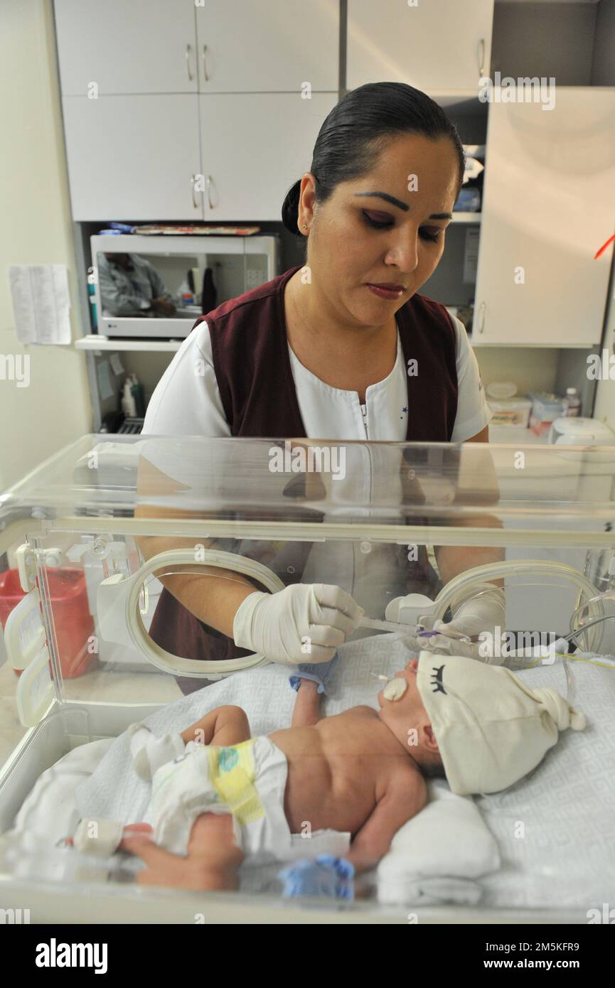 nurse with baby in nursery or intensive therapy or baby incubators ...
