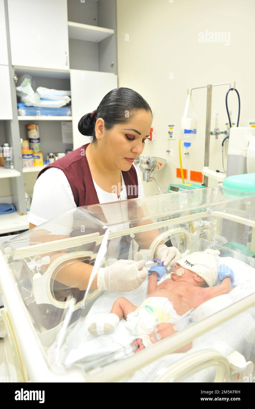 nurse with baby in nursery or intensive therapy or baby incubators ...