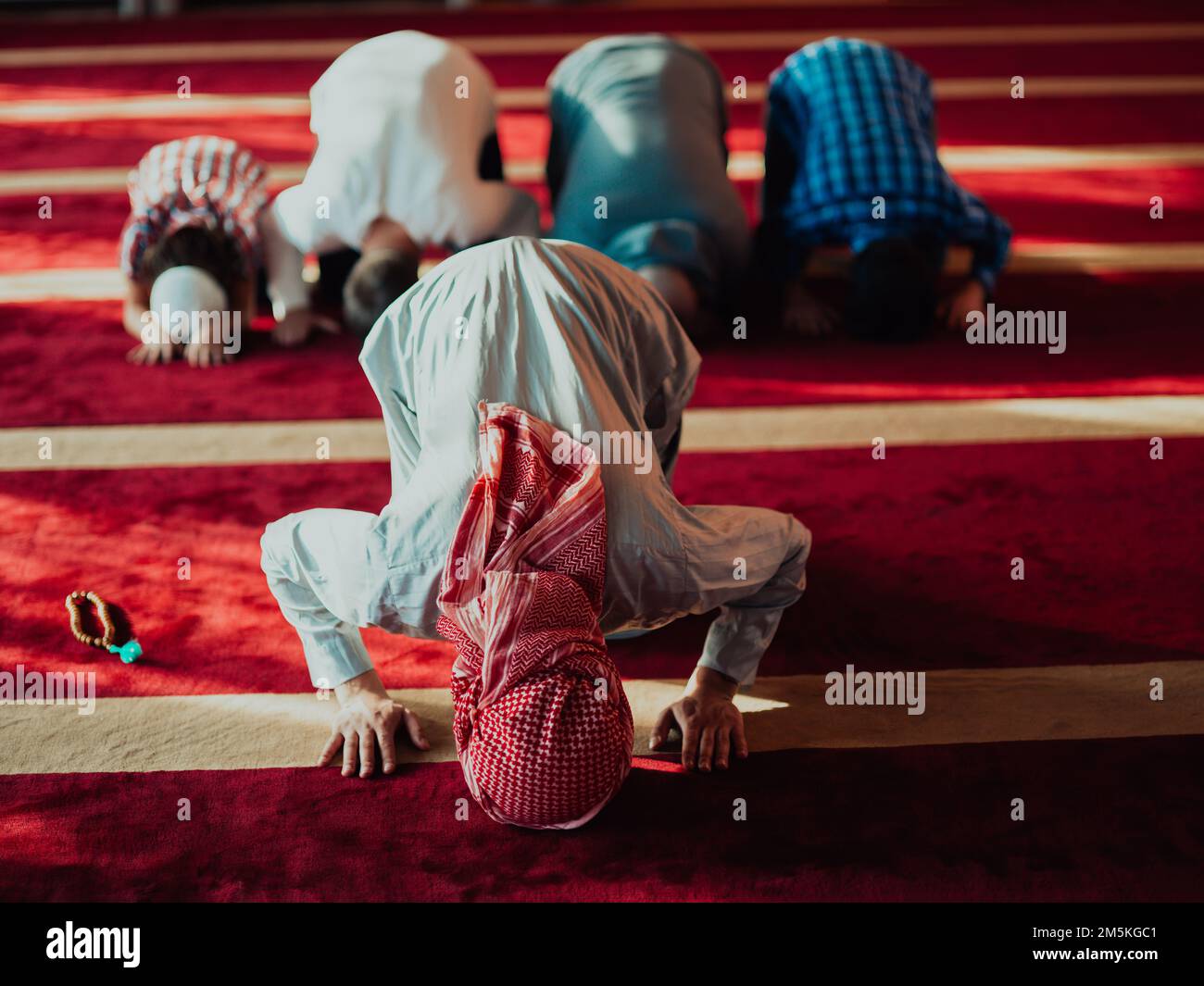 A group of Muslims in a modern mosque praying the Muslim prayer namaz ...