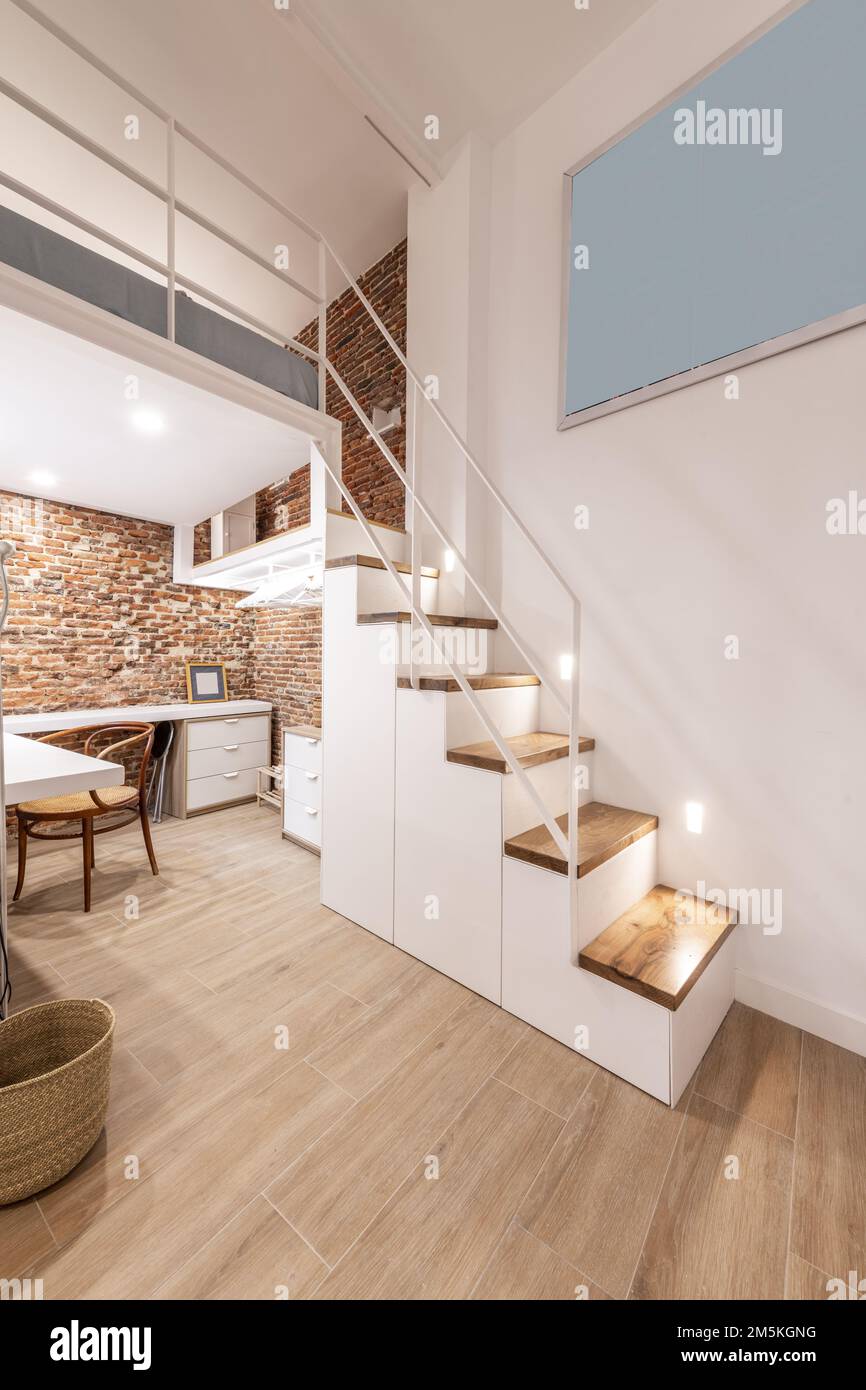 Loft apartment with a staircase with wooden steps and cabinets with ...