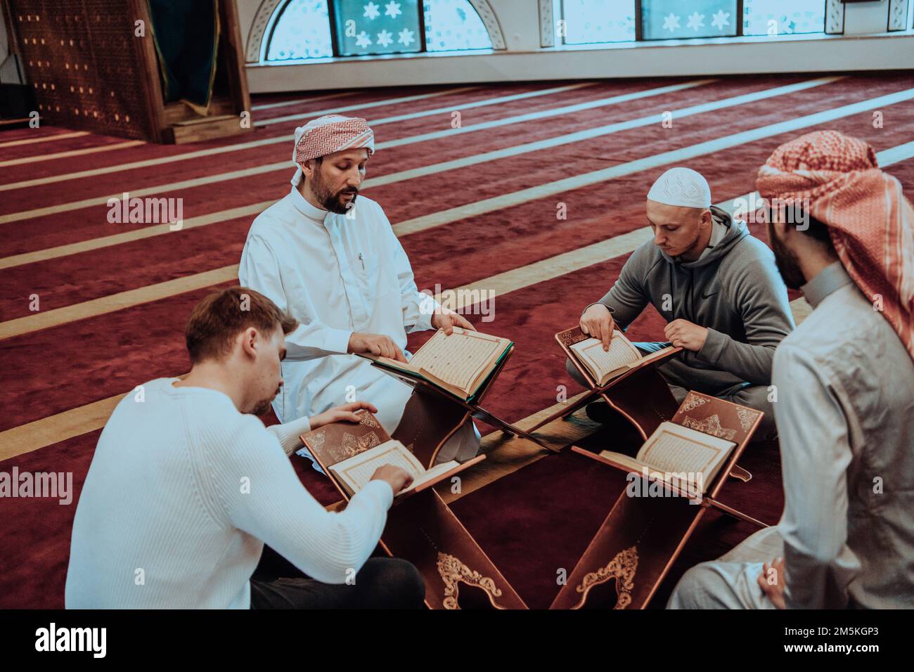 A group of Muslims reading the holy book of the Quran in a modern ...