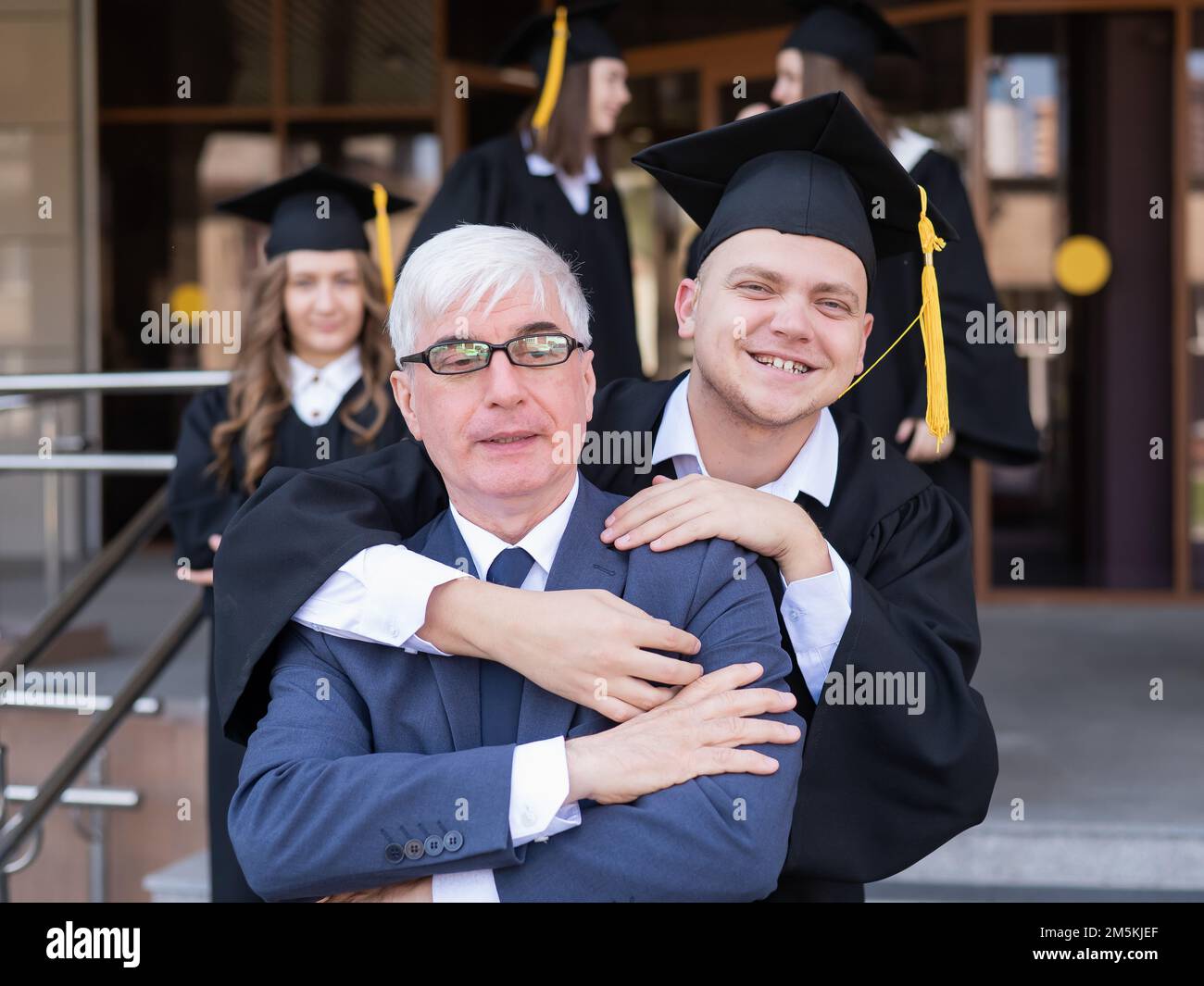 Father and son embrace at graduation. Parent congratulates university ...